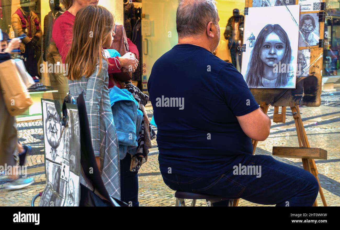 Adult street artist drawing portraits in a park in Lisbon, Portugal ...