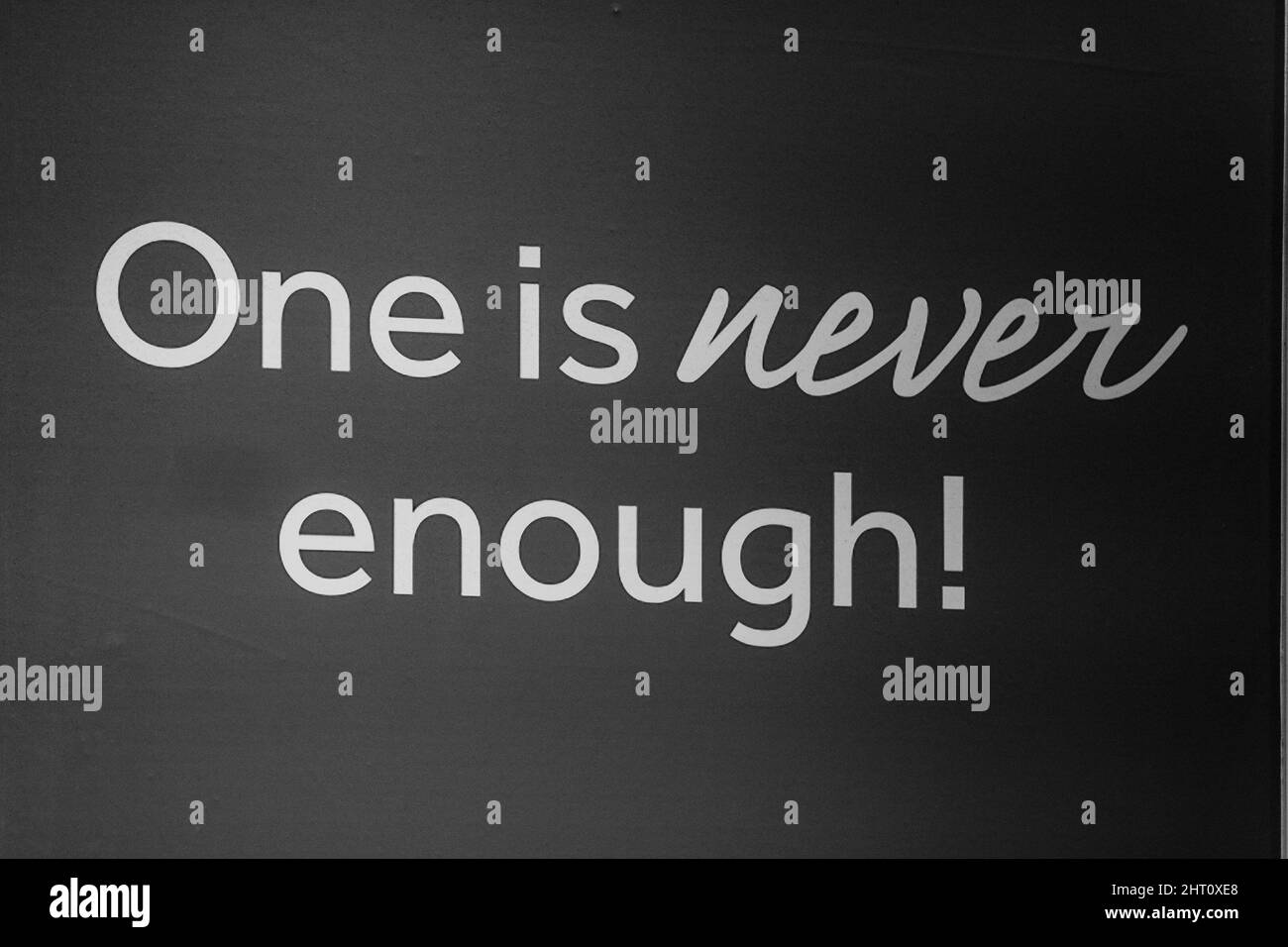 Slogan "One is never enough" on black background Stock Photo - Alamy