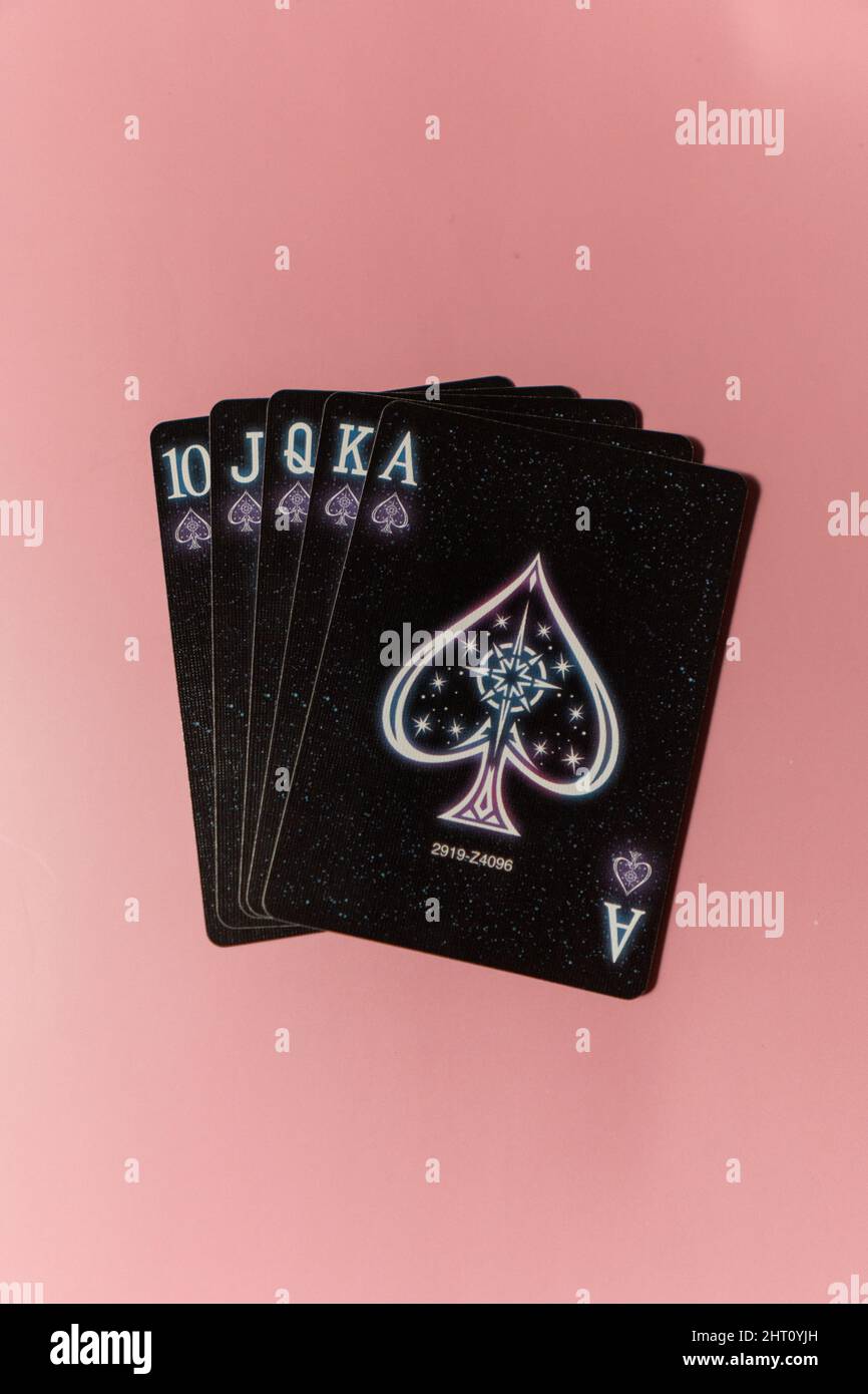Top view shot of top playing card on a pink background with other board ...