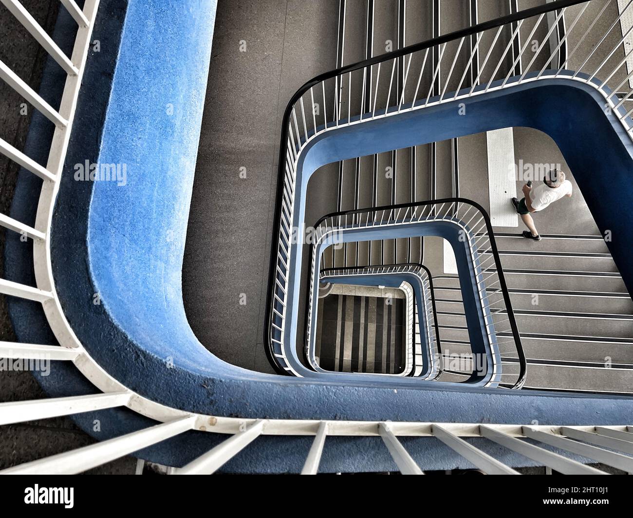 High angle shot of a person going down a spiraling blue staircase Stock ...