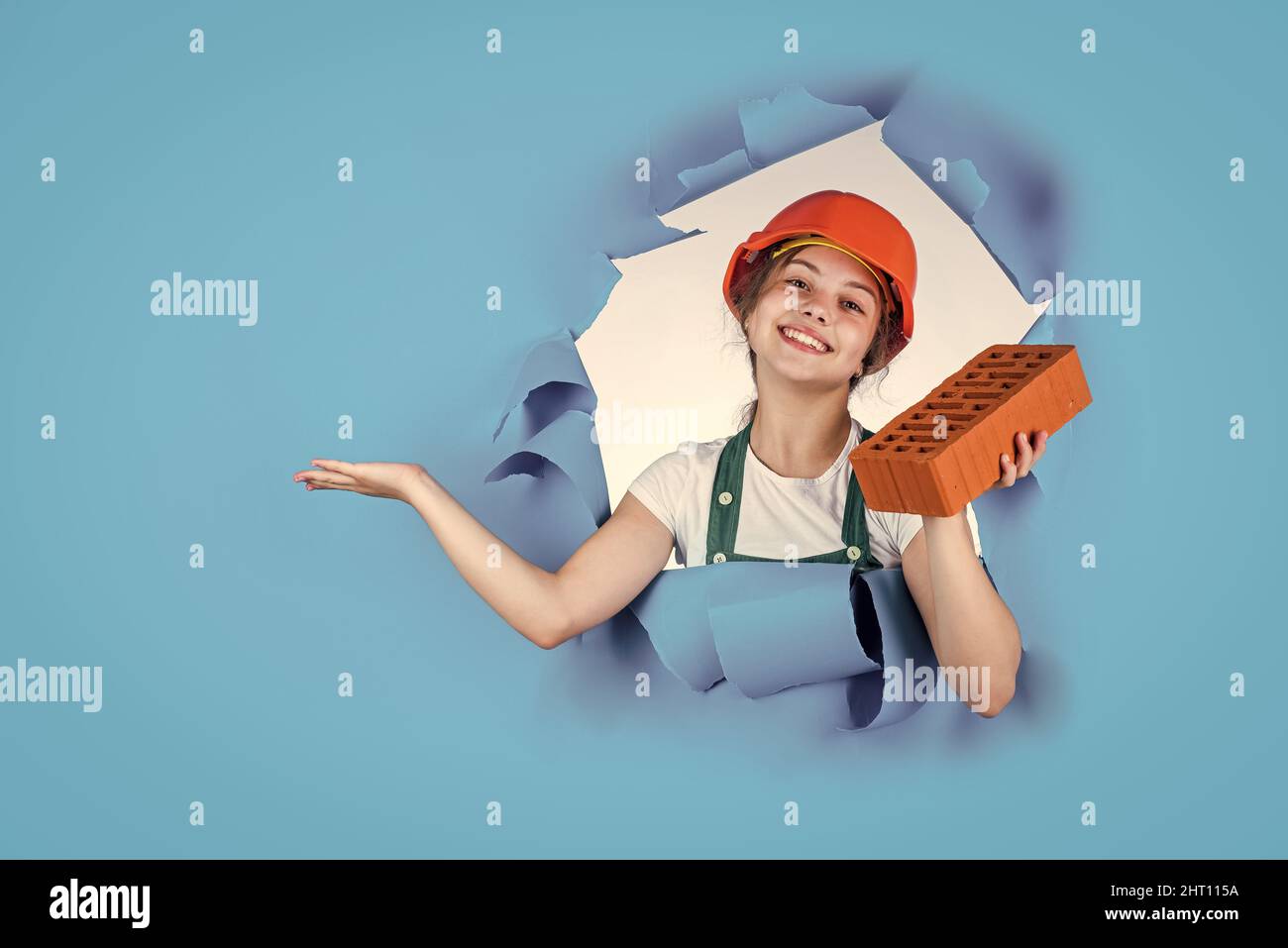 happy kid engineer with brick in hard hat, work tool, presenting ...