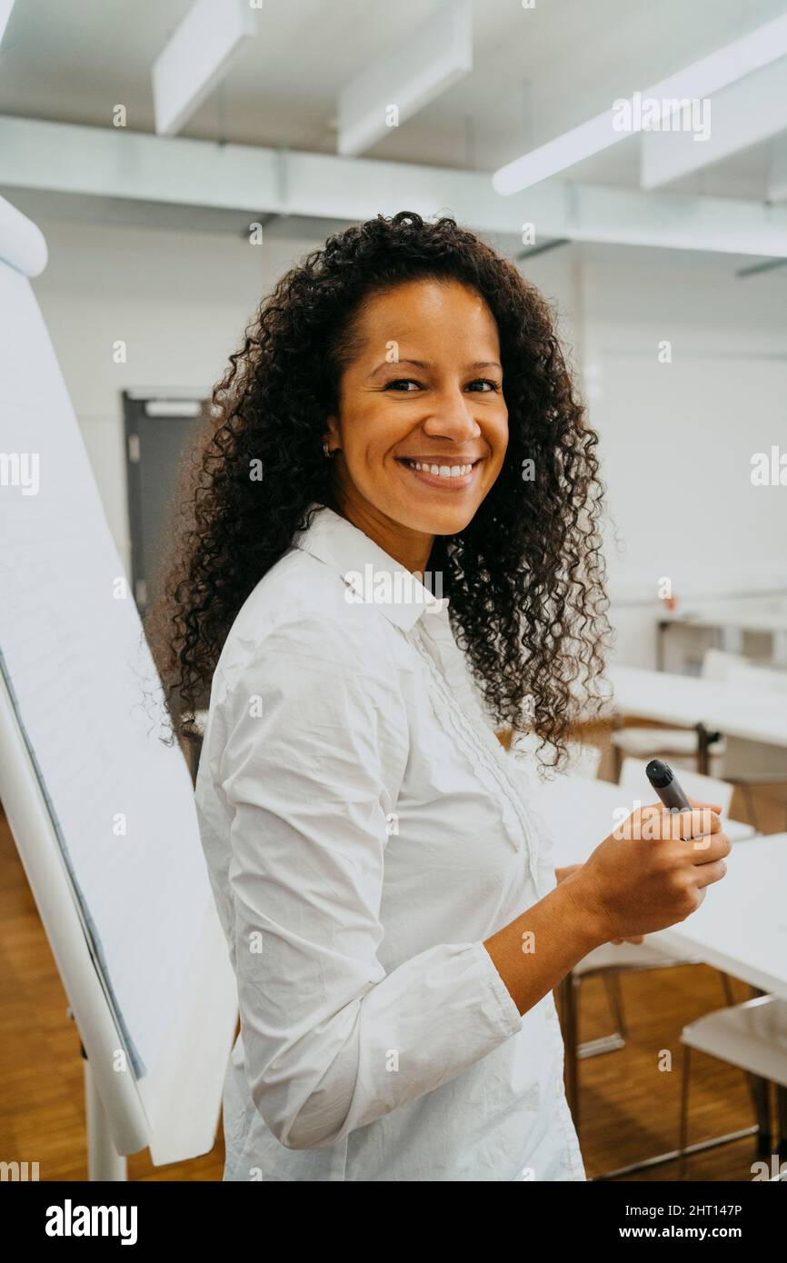 Side view portrait of smiling teacher with curly black hair standing by ...