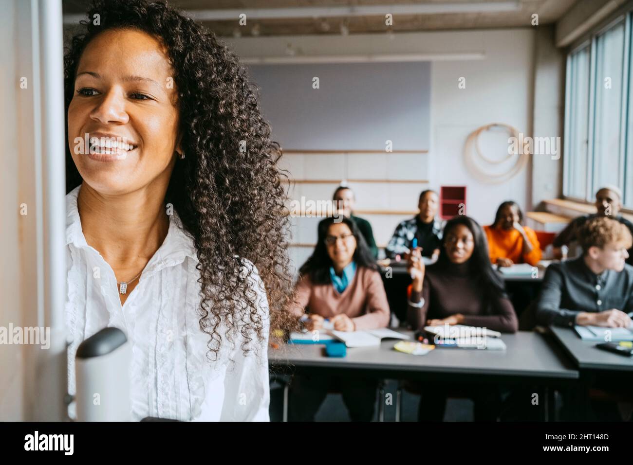 Smiling professor teaching university students in classroom Stock Photo ...