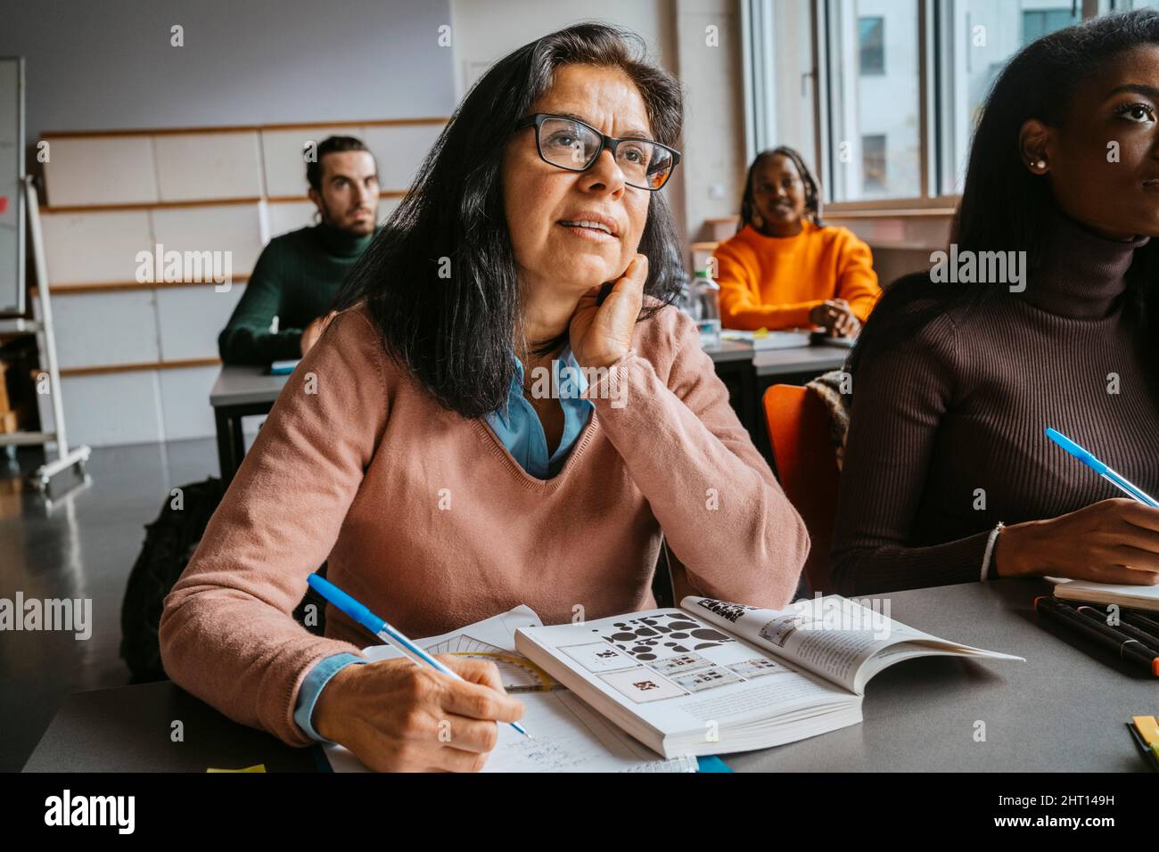 Mature female student sitting with friends in classroom Stock Photo - Alamy