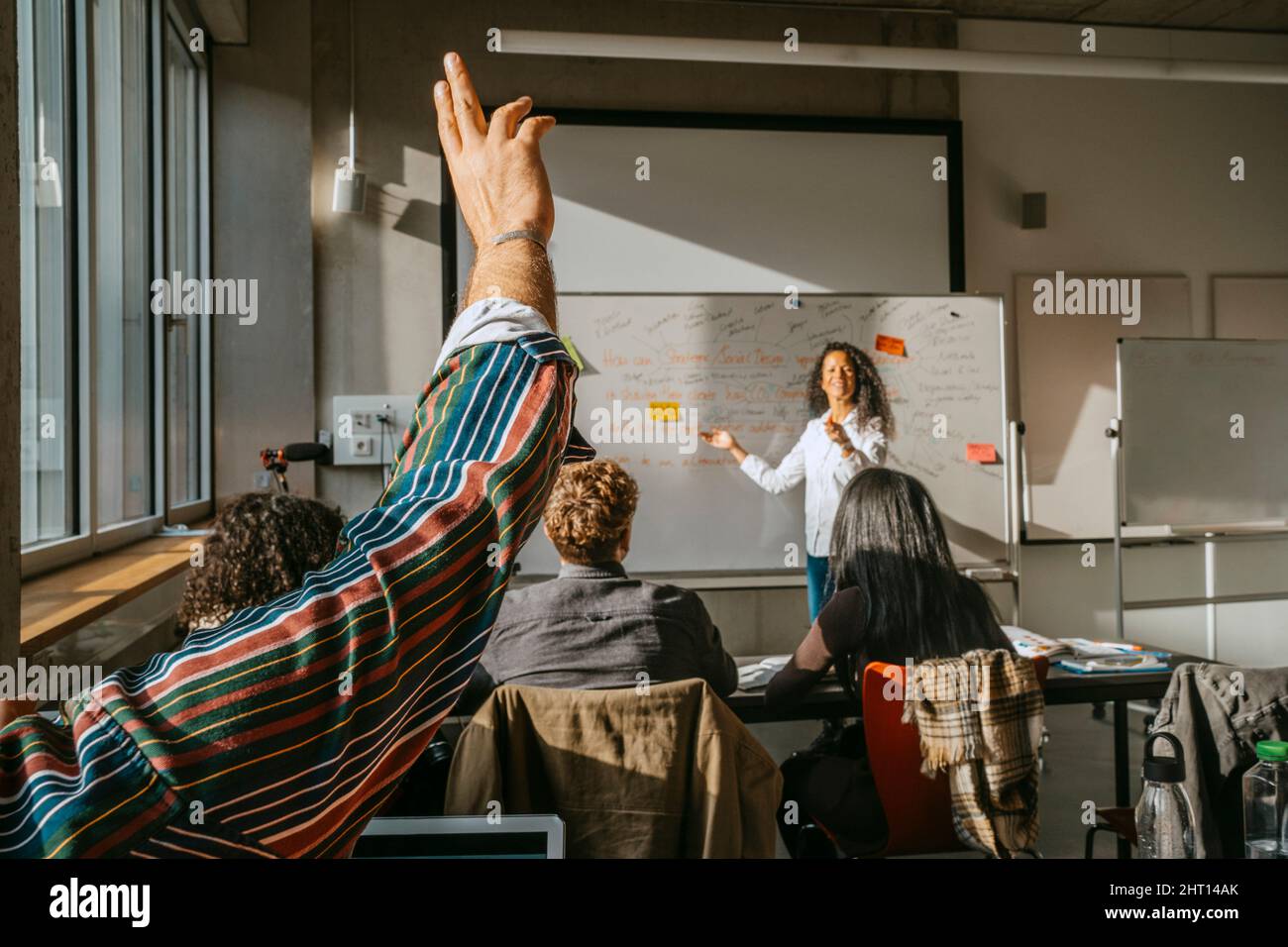 Cropped raised hand of male student with friends and teacher in ...