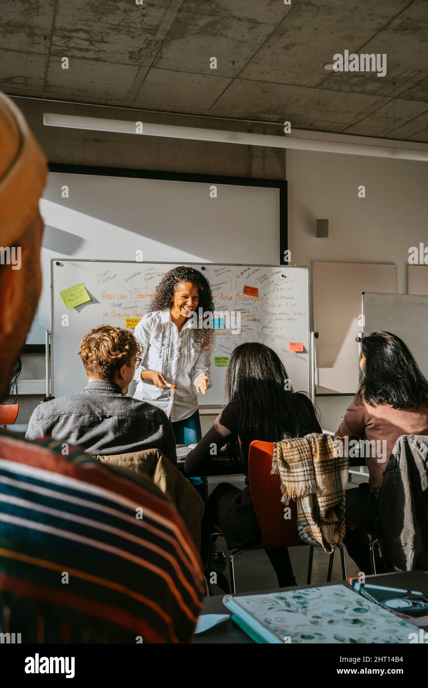 Smiling professor teaching students in classroom at university Stock ...