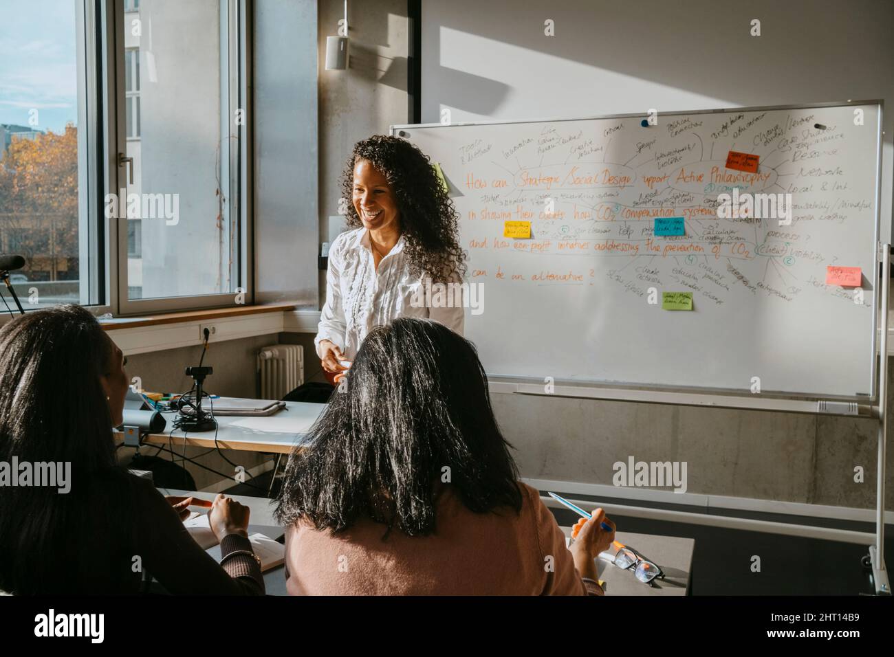 Cheerful professor teaching students sitting in classroom at university ...