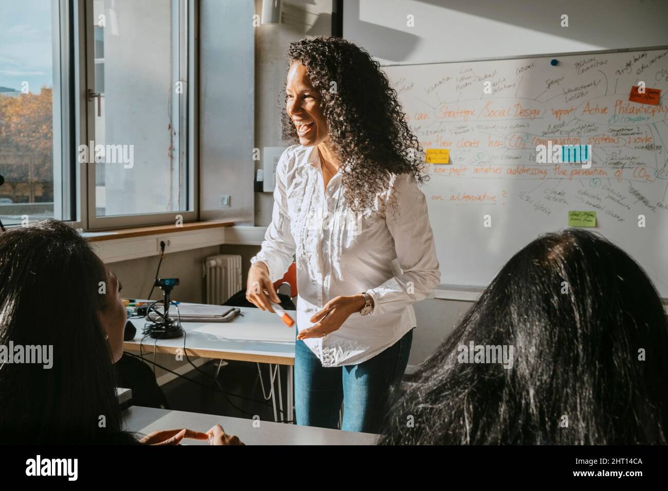 Cheerful professor teaching students sitting in classroom at community ...