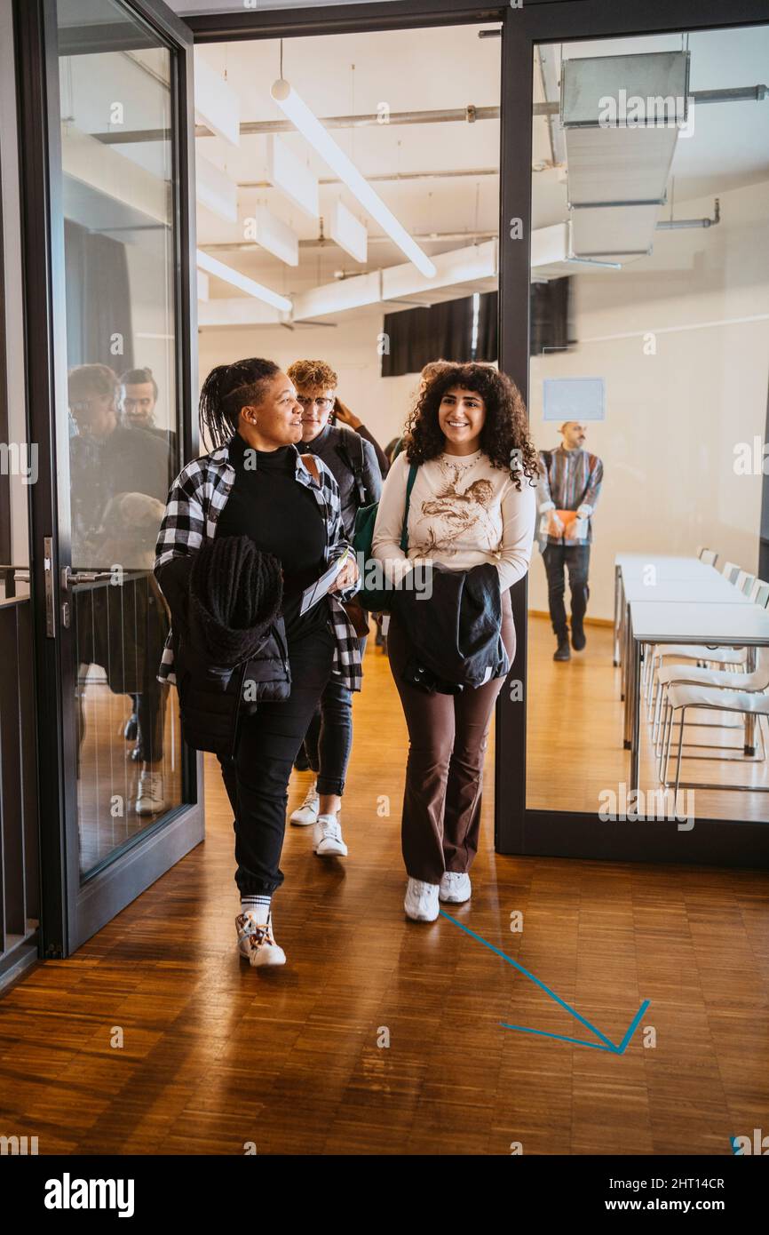 Smiling students leaving classroom while walking together Stock Photo ...