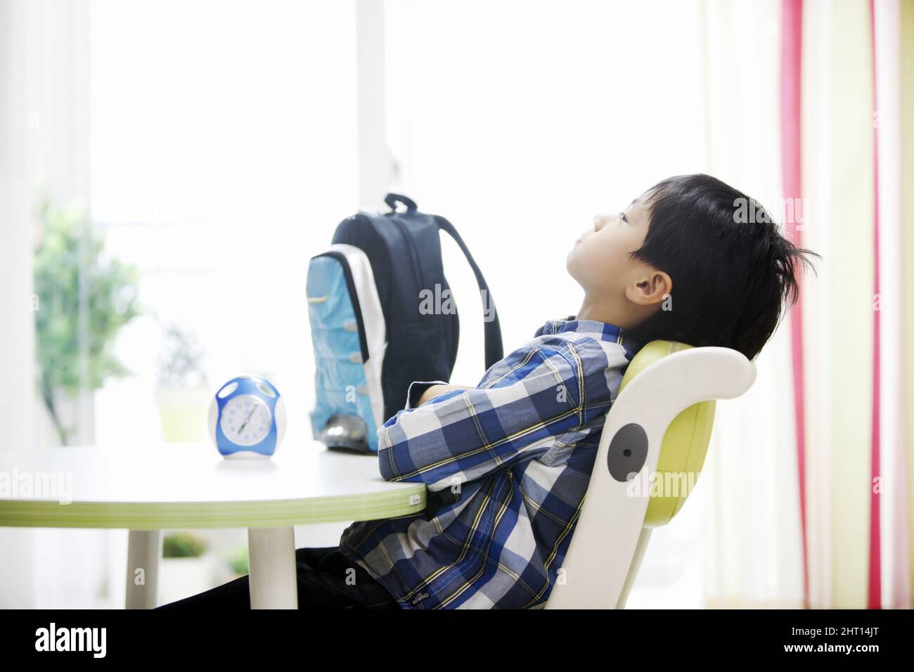 A child with arms crossed next to a backpack sits imagining and ...