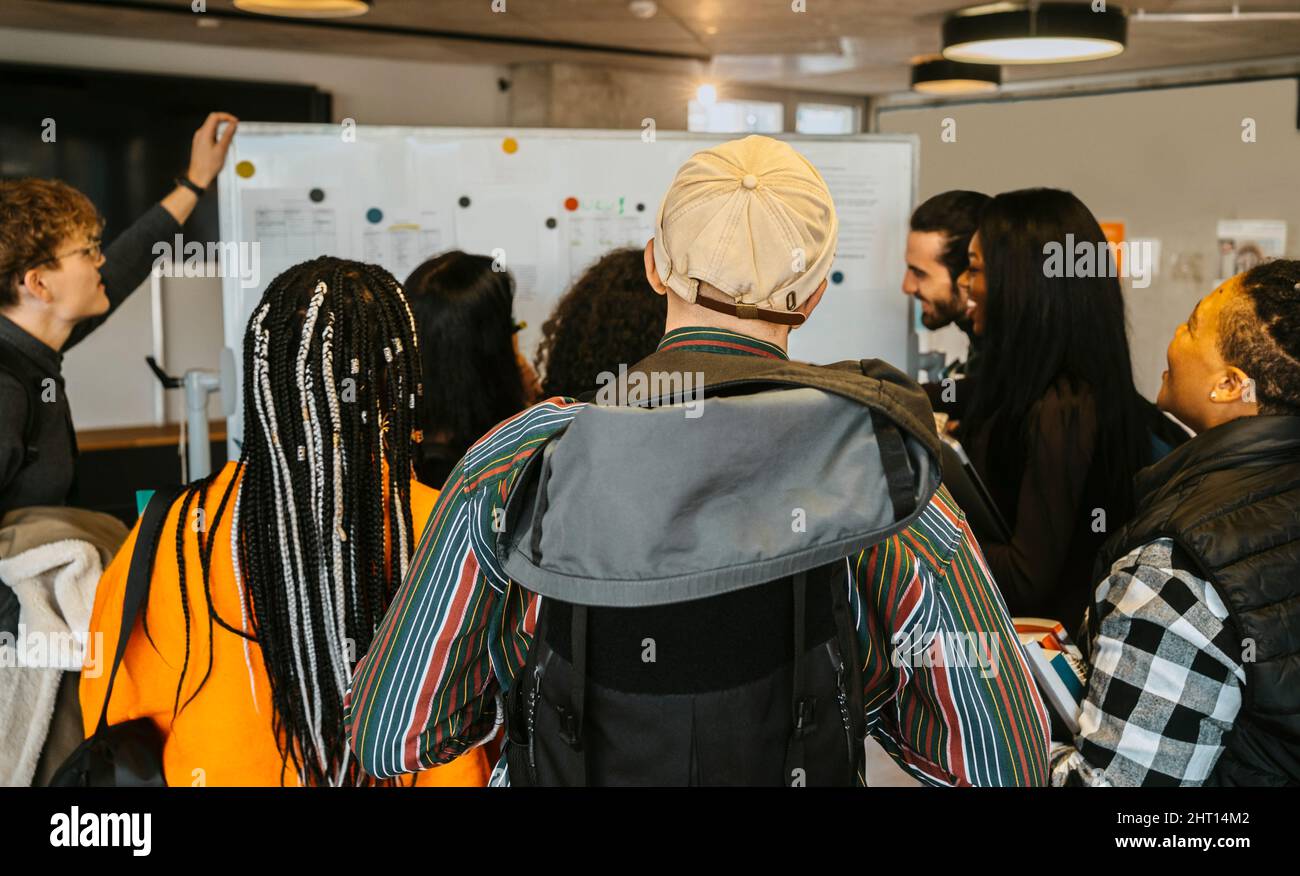 Multiracial adult students checking list with exam grades in university ...