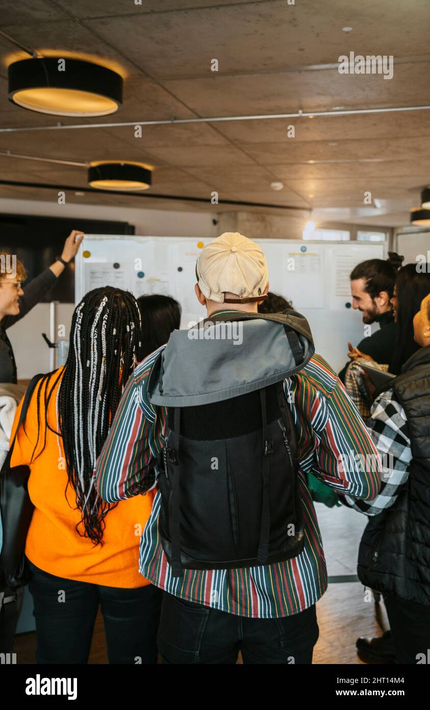 Multiracial adult students checking list with exam grades in community ...