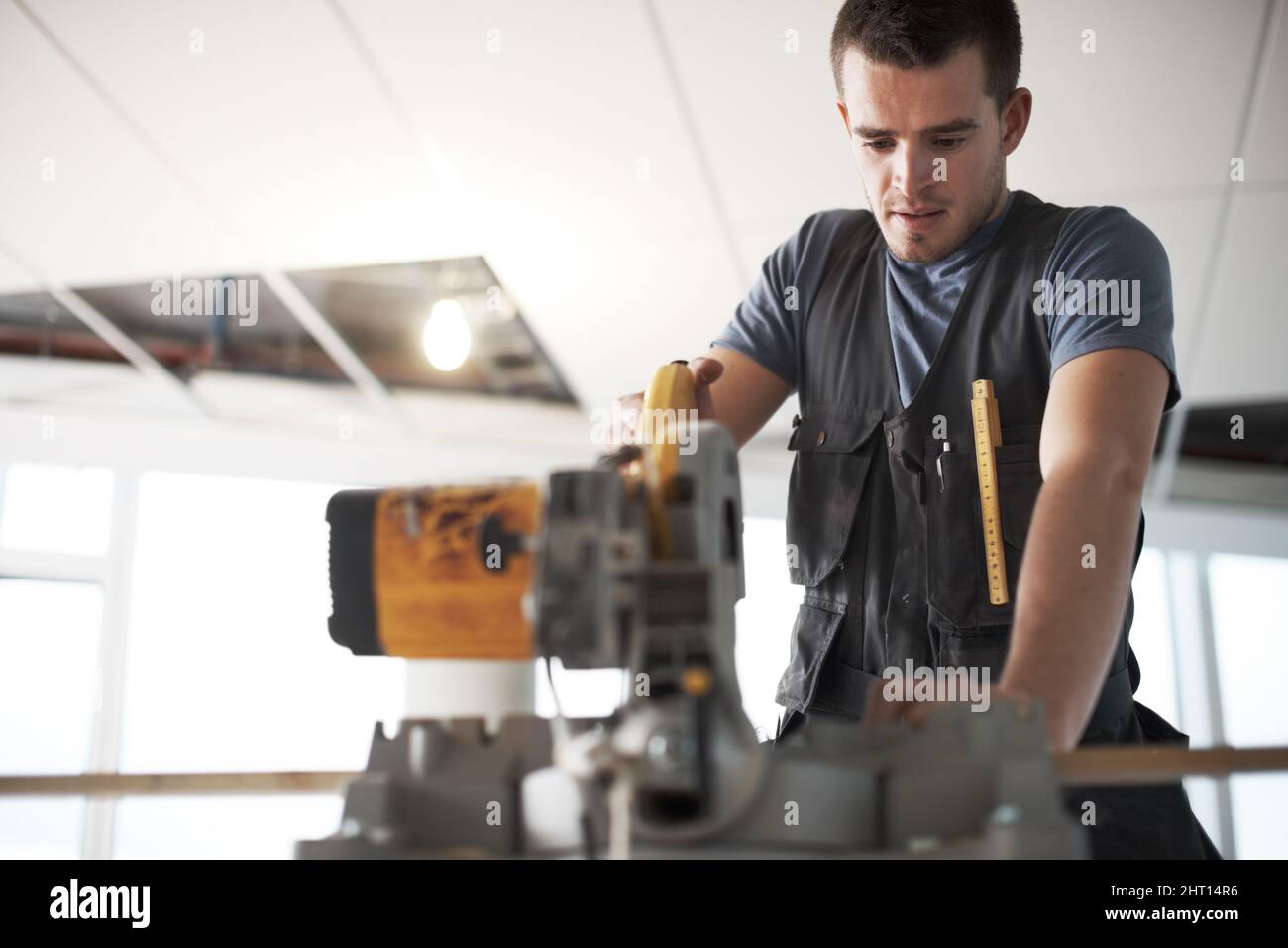 Hes experienced at this job. Young contractor using a saw while on a ...