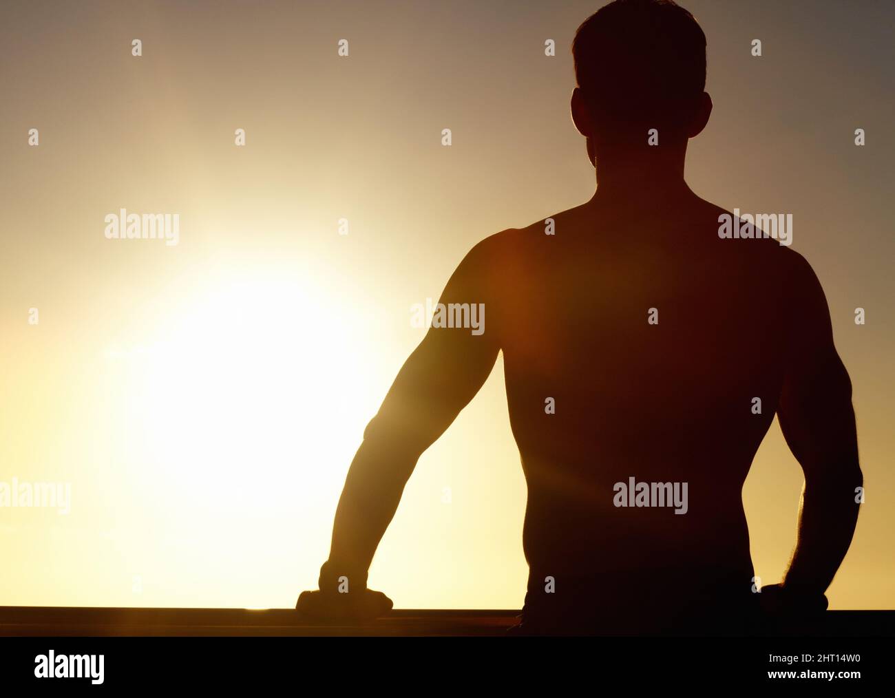 Facing a bright future. A silhouette of a muscular man looking at the ...