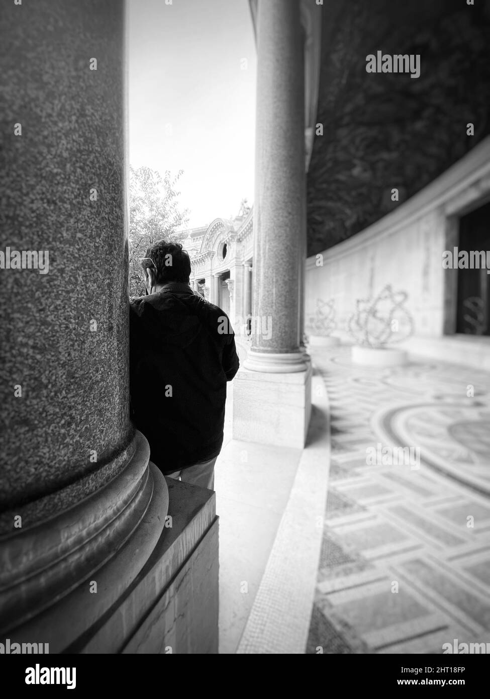 Grayscale of a man leaning on a pillar in Paris, France Stock Photo - Alamy
