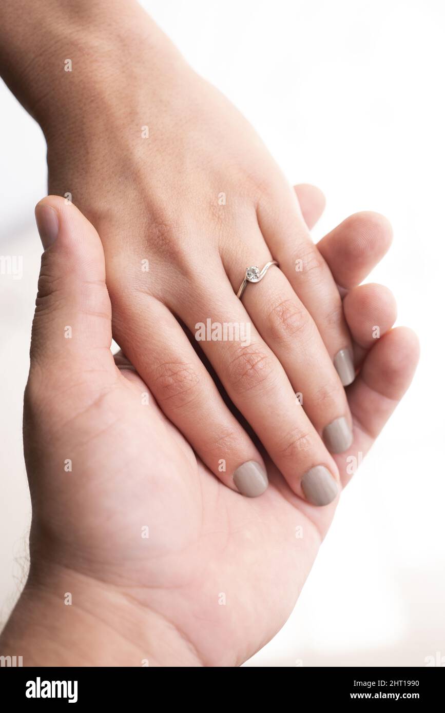 Closeup of the hands of a couple touching each other on a white ...