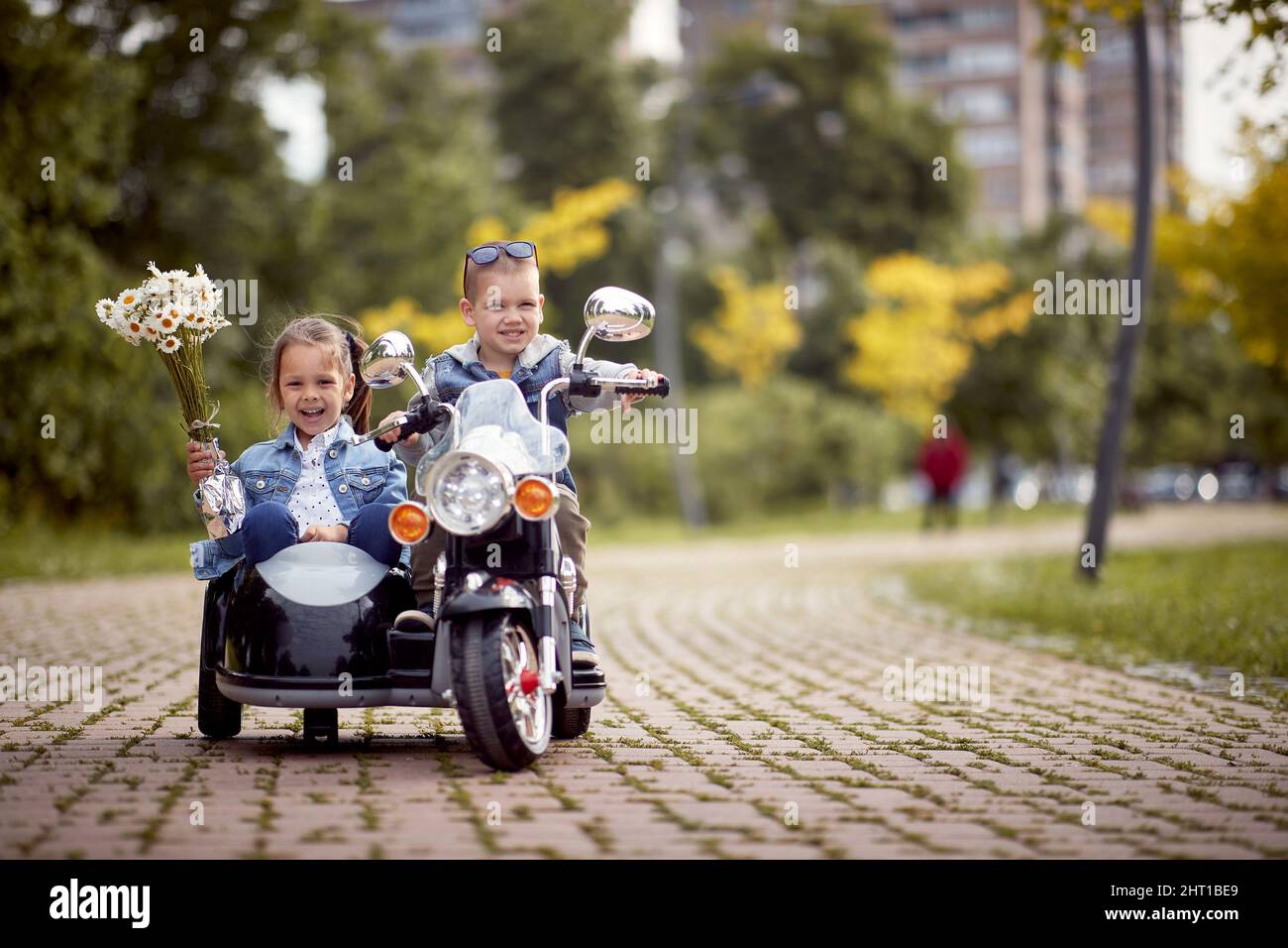 little kids driving in motorcycle toy on battery in park Stock Photo ...