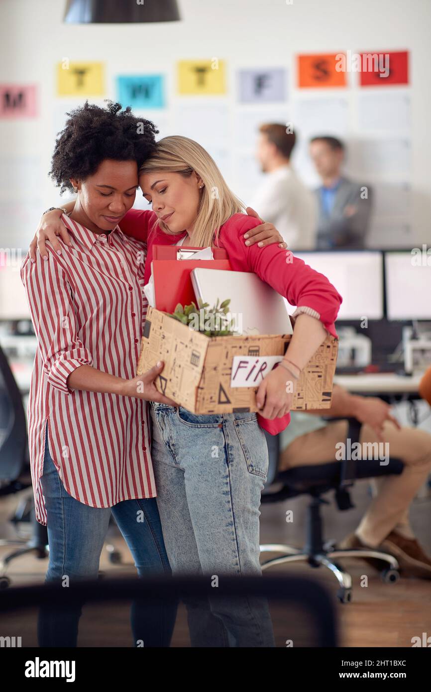 A young female clerk in a sad atmosphere in the office is hugging and ...