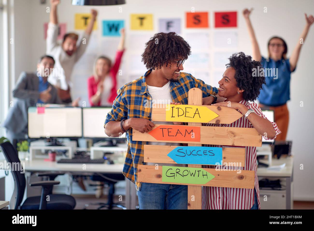 Young cheerful colleagues are promoting company slogans and posing for ...