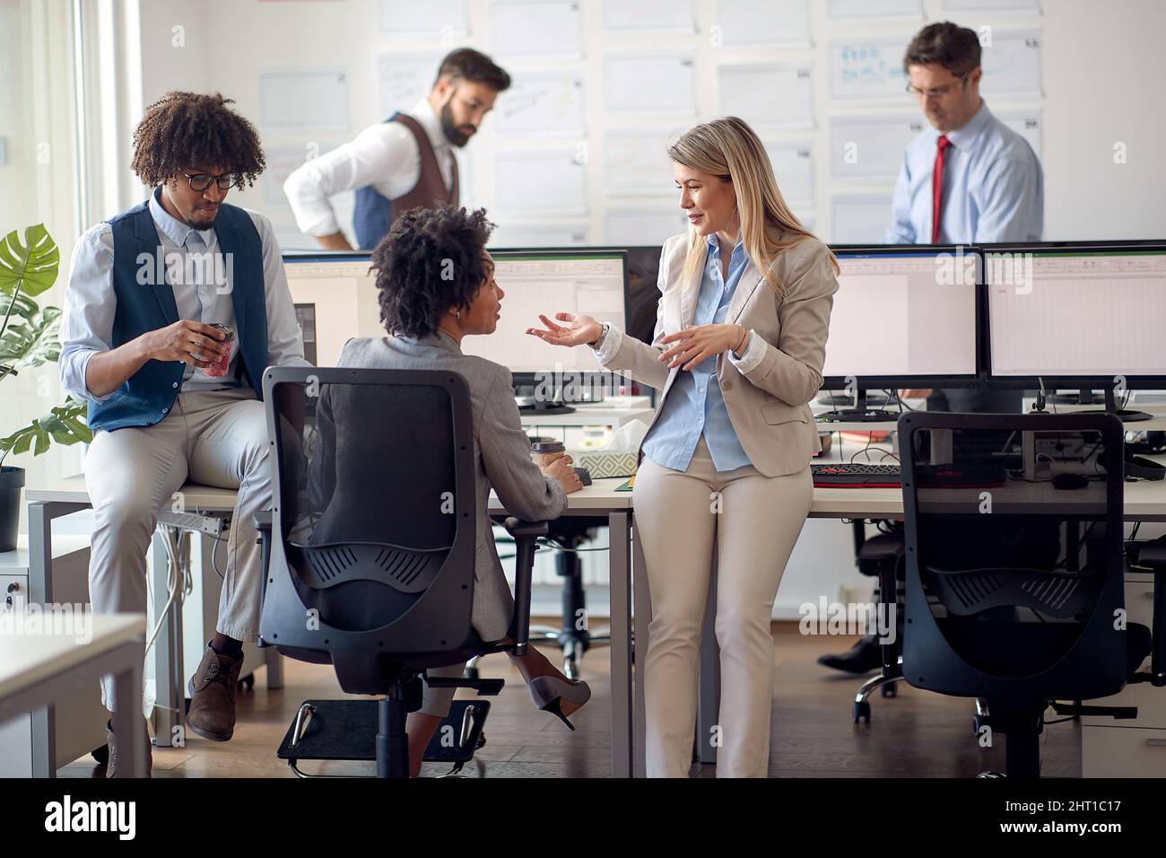 Group of young professional coworkers discussing together in the office ...