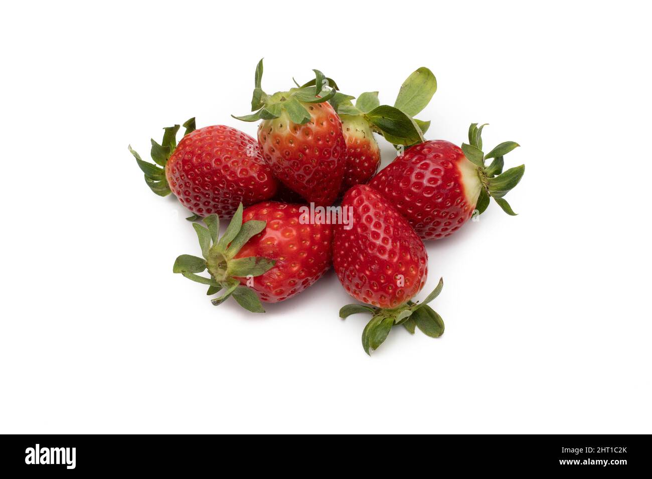 A handful of whole strawberries with their green leaves laid out in a ...