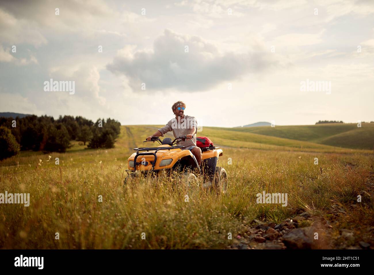 A young man is riding a quad on a beautiful sunny day in the nature ...