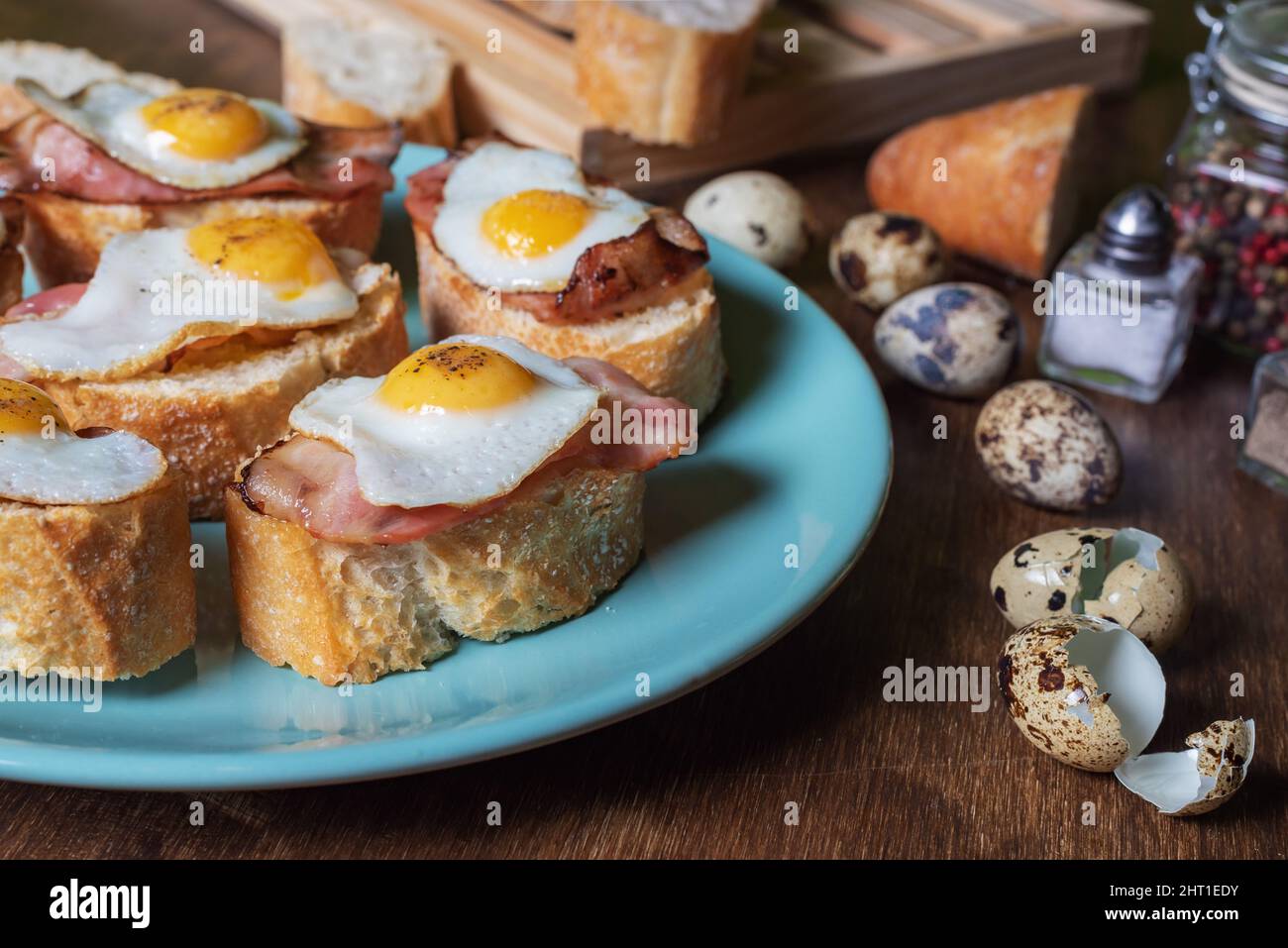 Slice of bread with bacon and grilled quail egg,on a wooden table Stock ...
