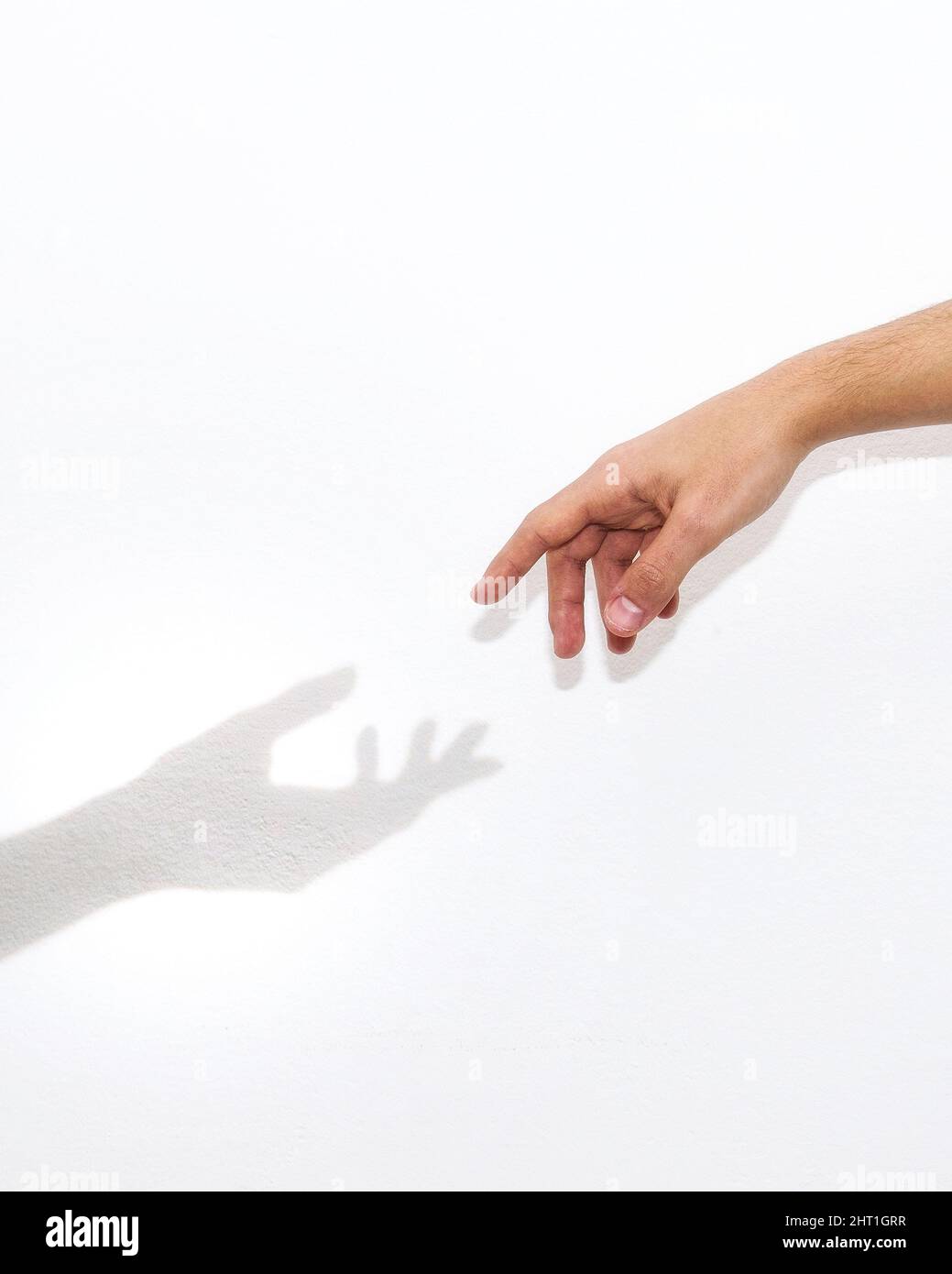 Hand trying to reach the silhouette of a shadow hand on a white ...
