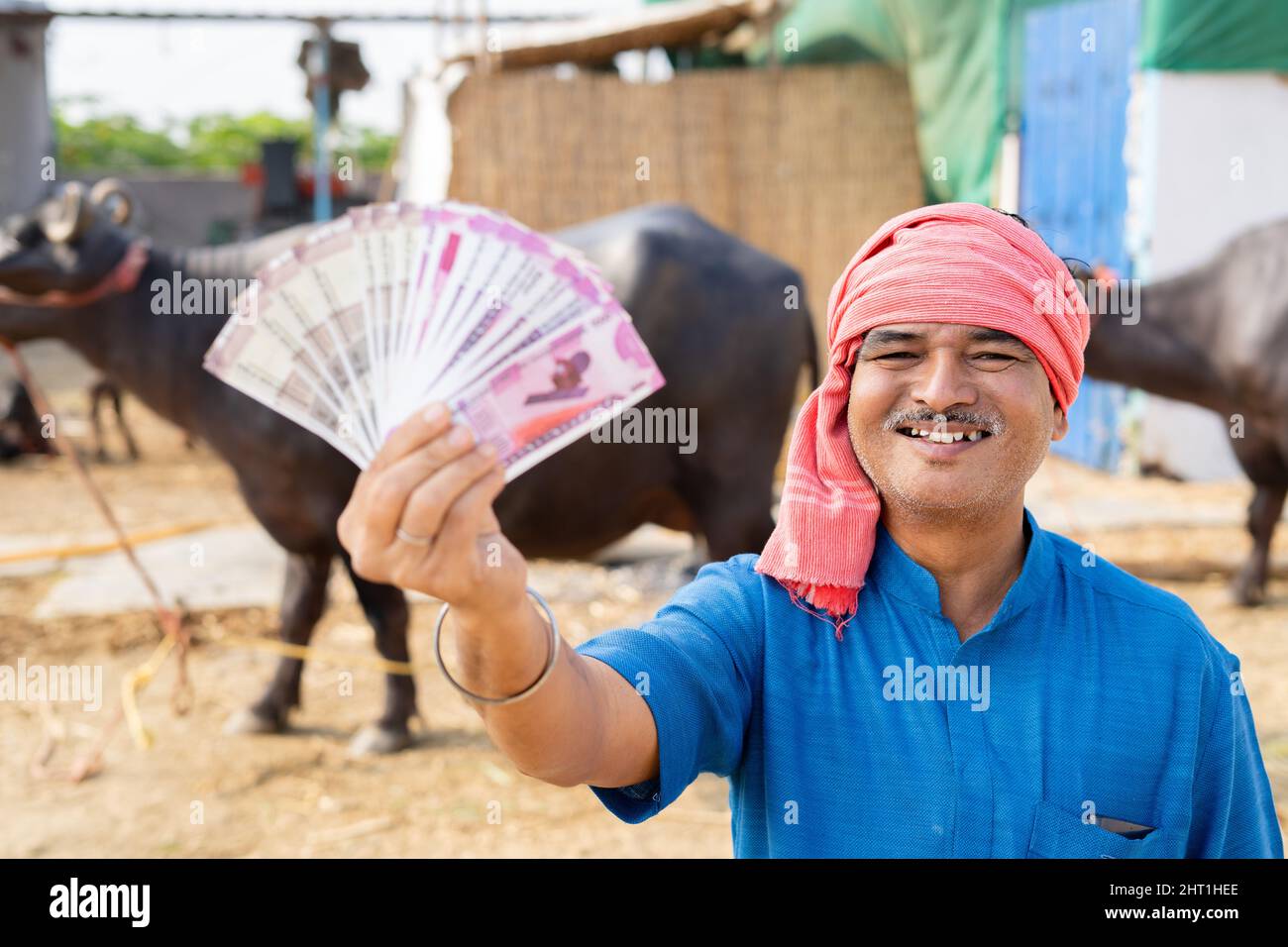 Confident milk dairy farmer showing indian currency money by looking at ...