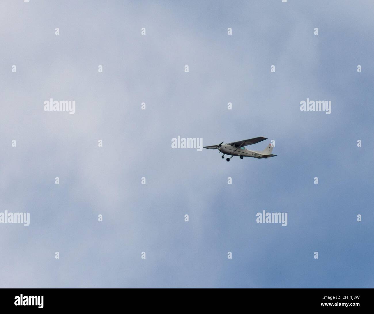 Low angle shot of the Cessna Plane flying under a blue cloudy sky in ...