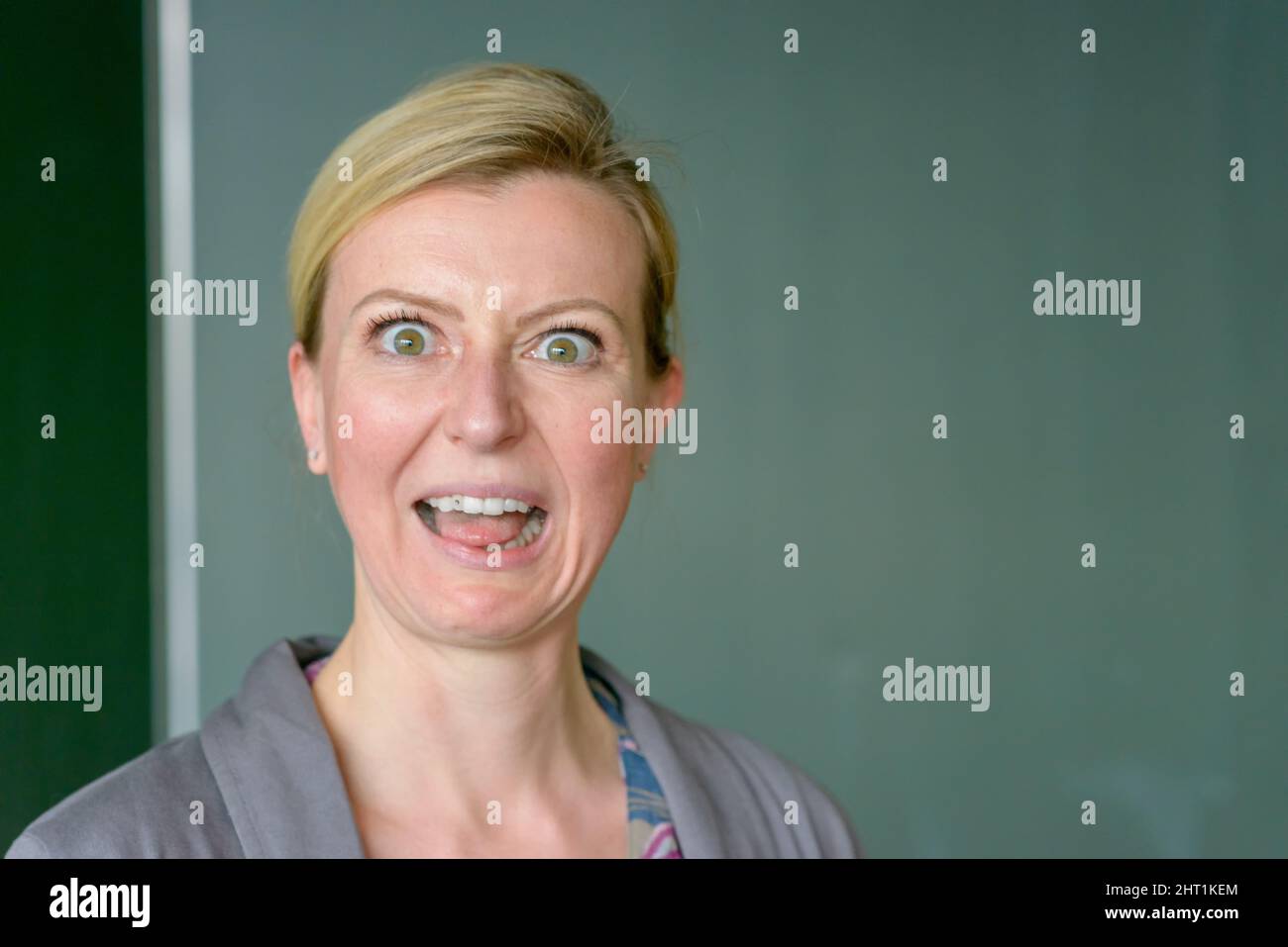 Teacher pulling an aghast face in front of blackboard staring at the ...