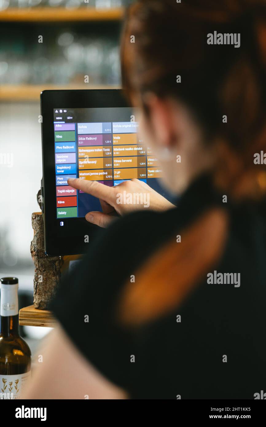Vertical closeup of the employee creating orders of food and beverages ...