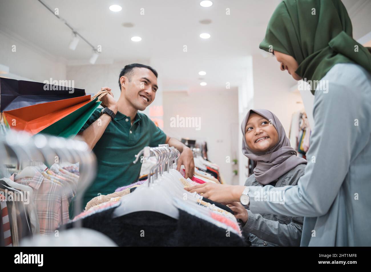 muslim family shopping together at the mall buying some new clothes ...