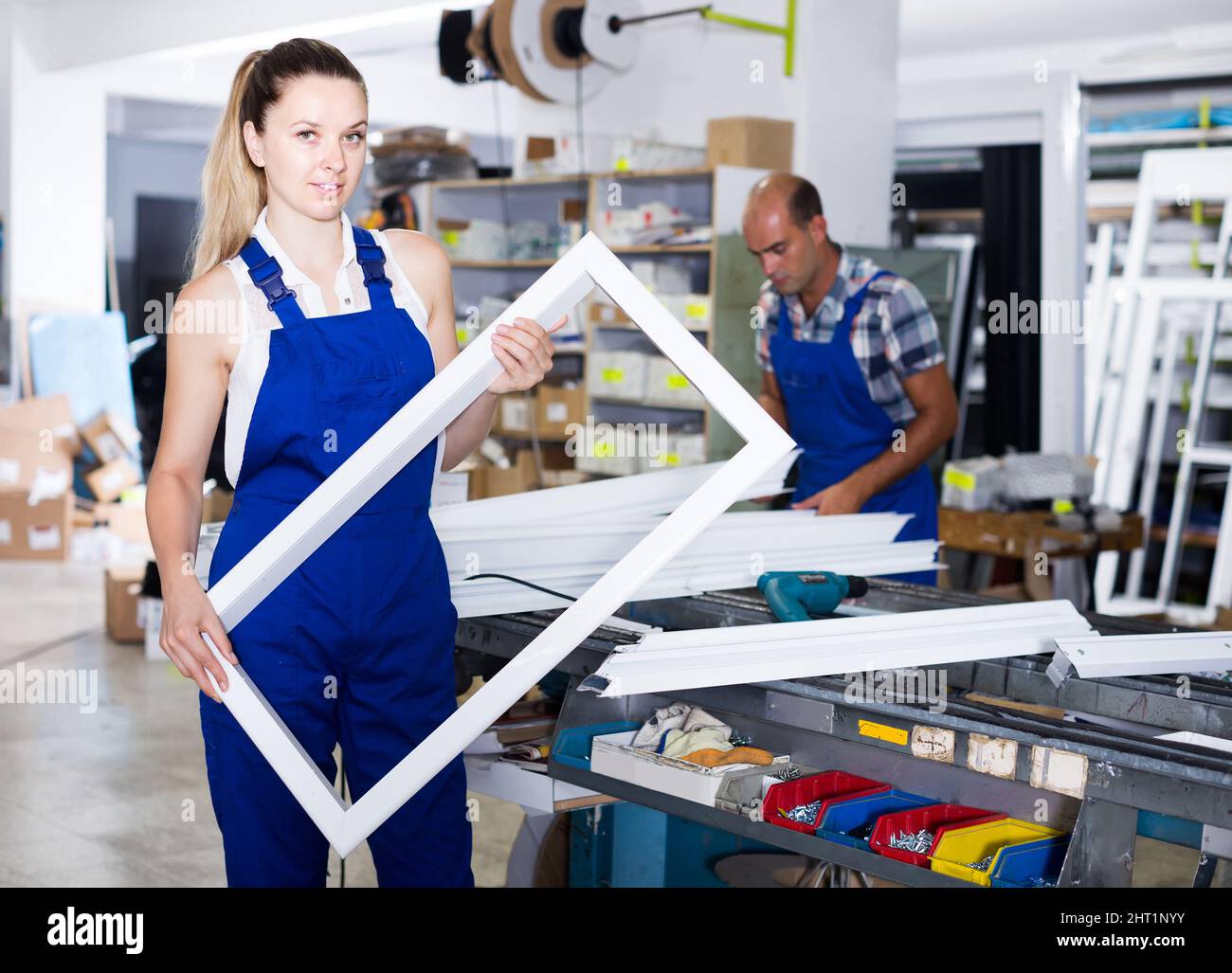girl in workwear with window frame from pvc profile standing in ...