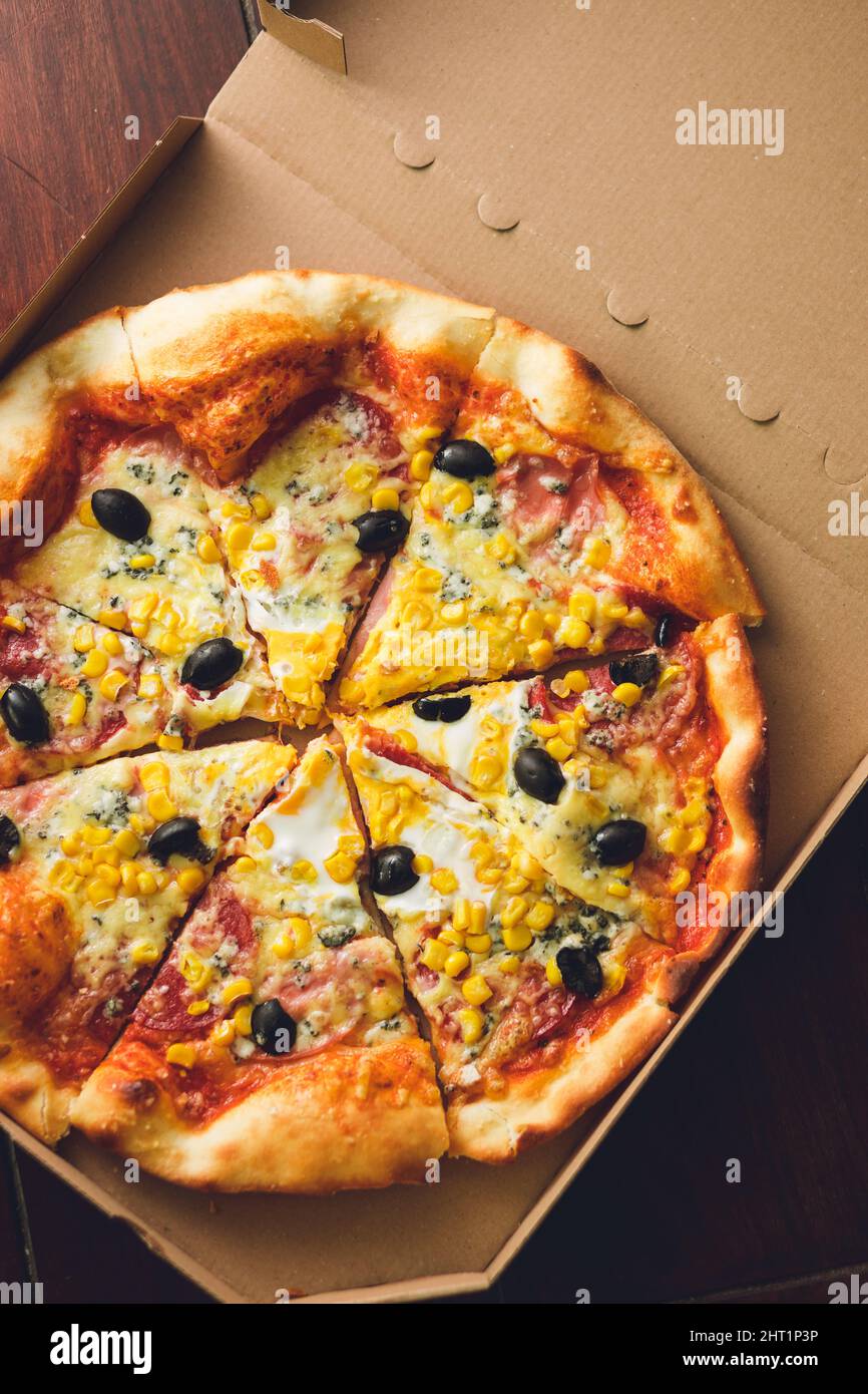 Vertical closeup of the pizza with tomato base, cheese, pepperoni, ham ...