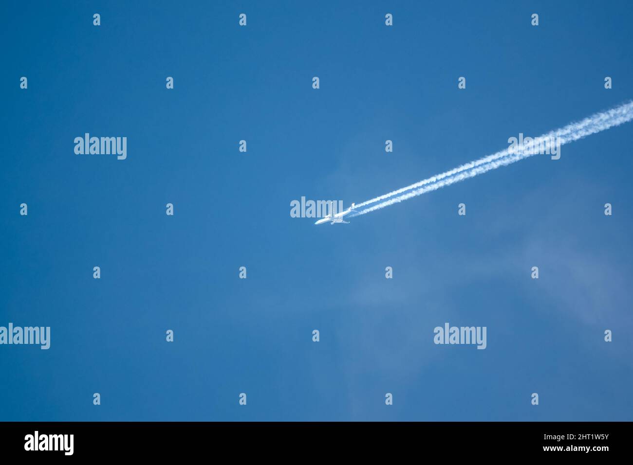 high altitude contrails from a twin engine jet airliner in a deep blue ...