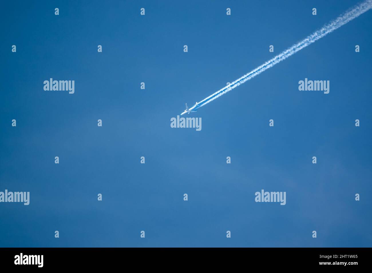 high altitude contrails from a twin engine jet airliner in a deep blue ...