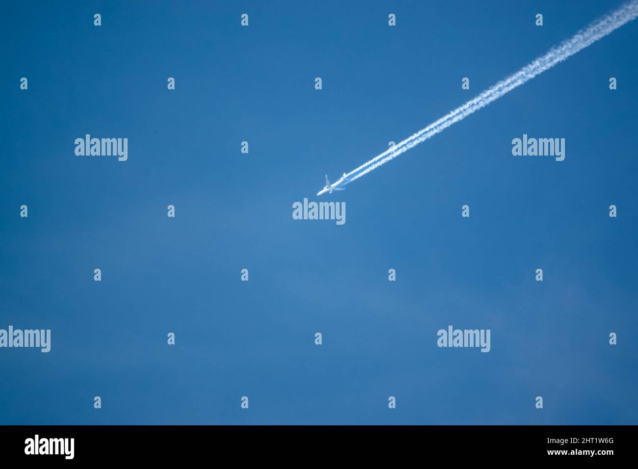 high altitude contrails from a twin engine jet airliner in a deep blue ...