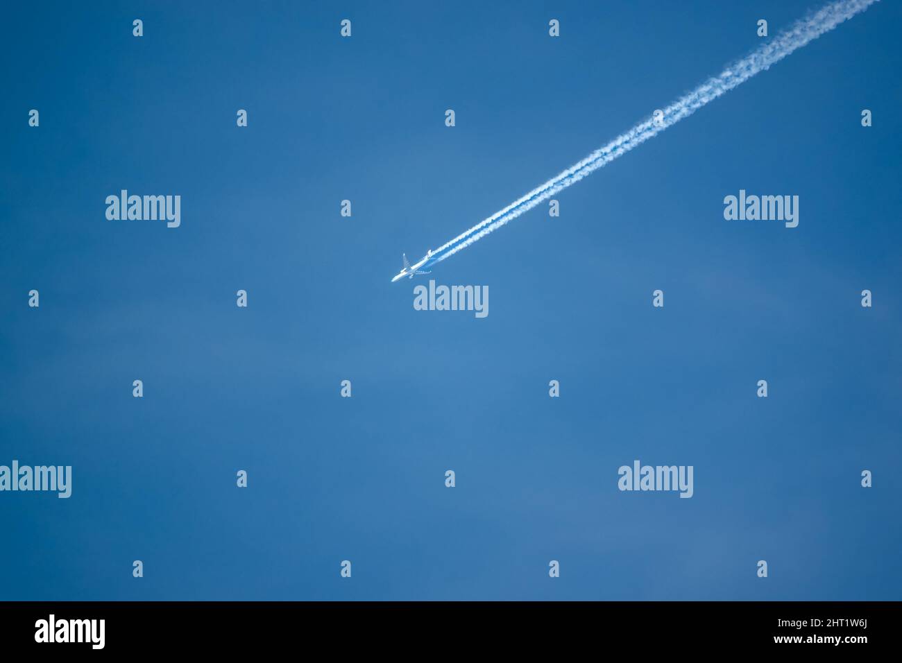 high altitude contrails from a twin engine jet airliner in a deep blue ...