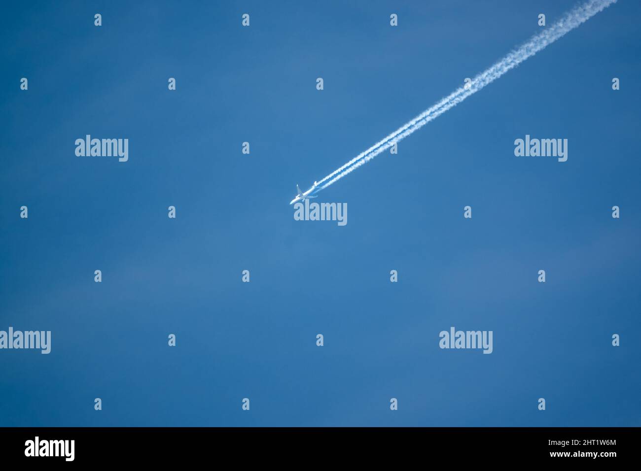 high altitude contrails from a twin engine jet airliner in a deep blue ...