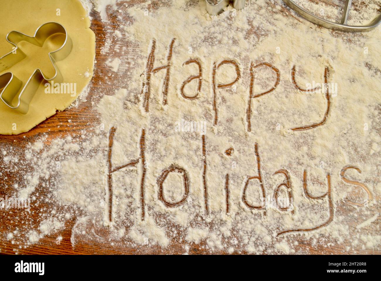 Happy Holidays written text in flour, on the counter, with metal ...