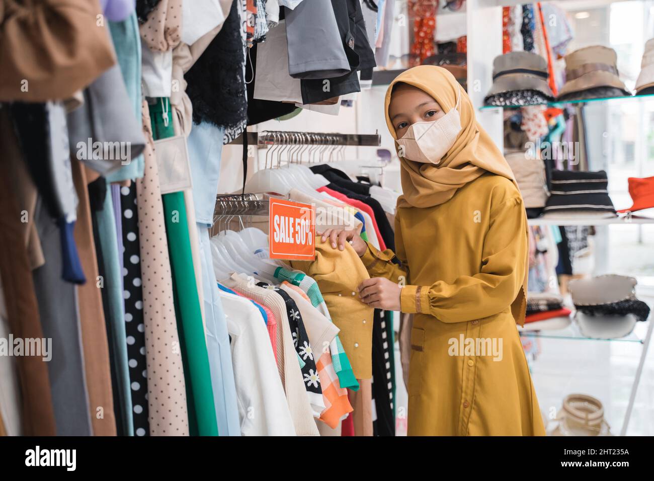Little girl shopping new clothes in a shop at the mall Stock Photo - Alamy