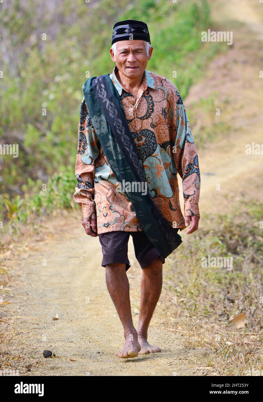 Vertical closeup of the old man in traditional clothes walking along ...