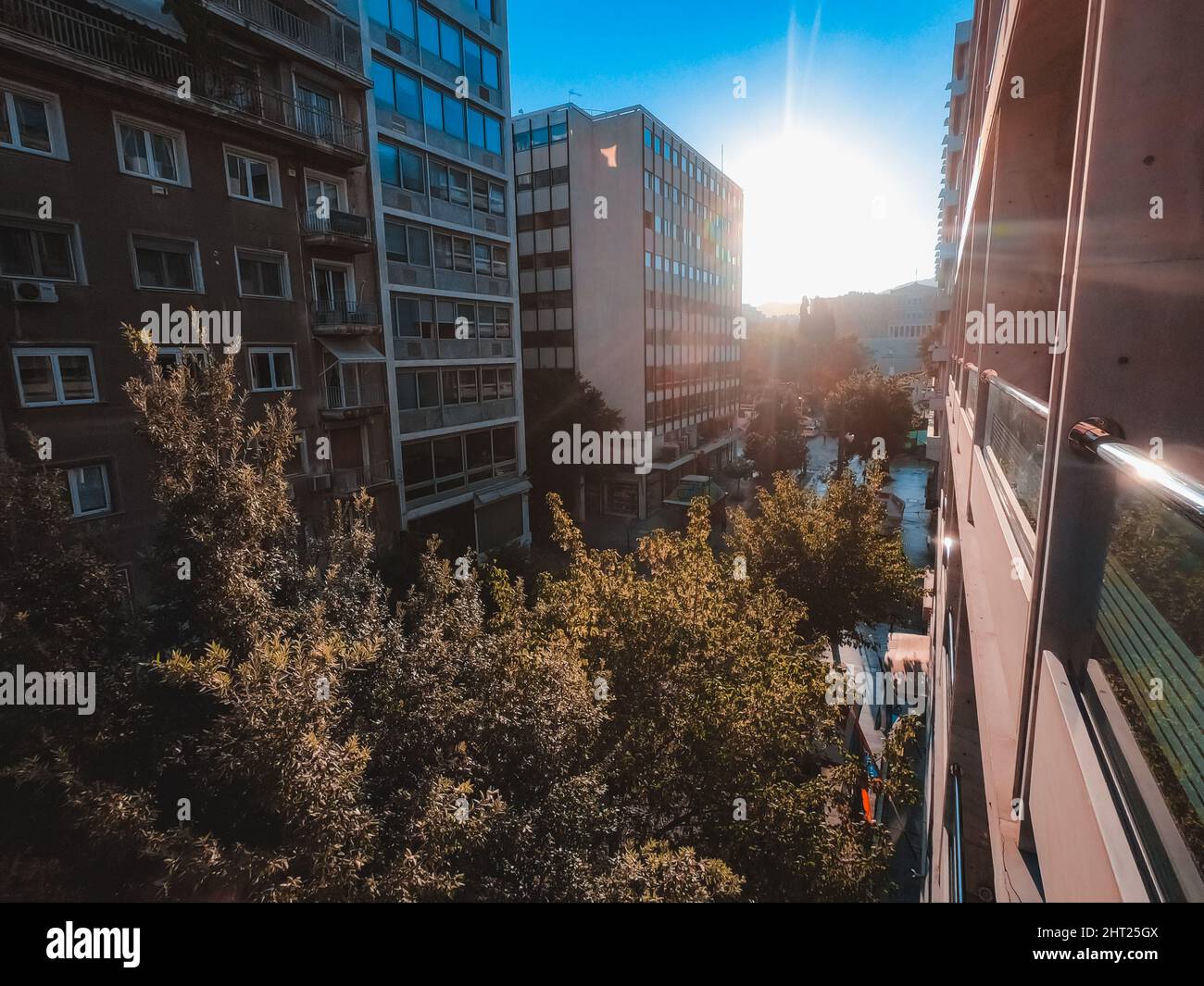 Bright sun in the horizon against city buildings in Athens, Greece ...