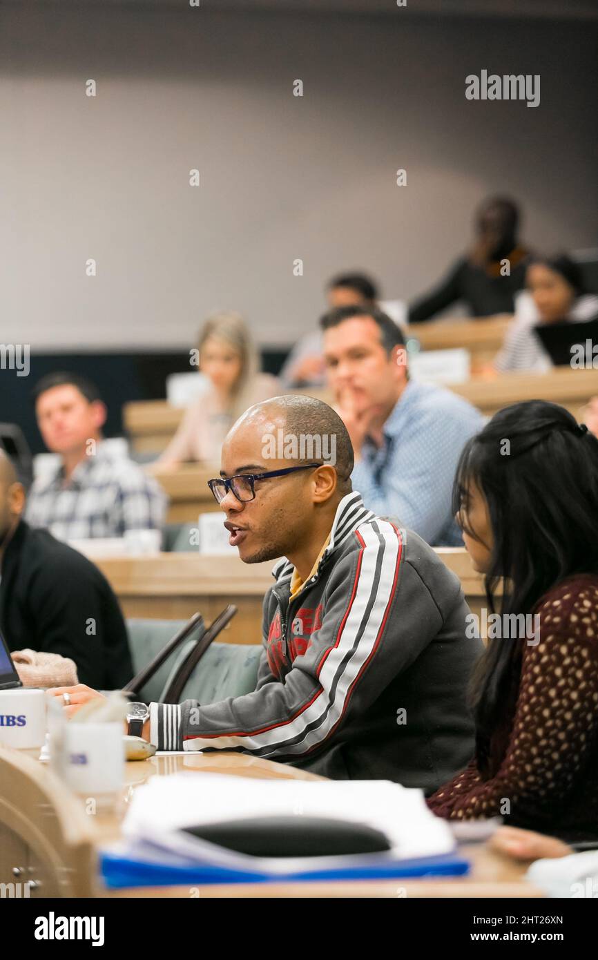 Diverse adult delegates attending a business lecture in a classroom ...