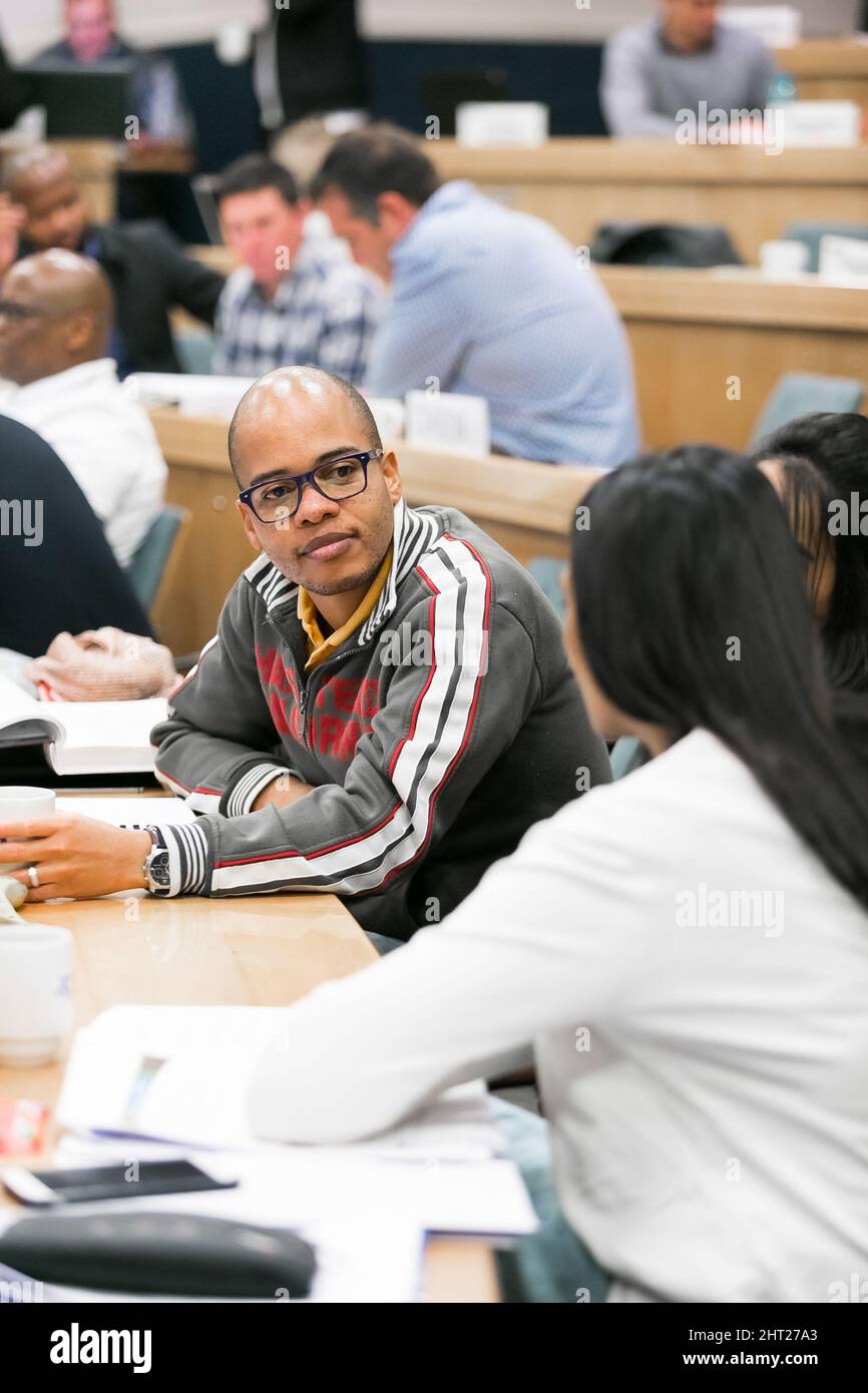 Diverse adult delegates attending a business lecture in a classroom ...