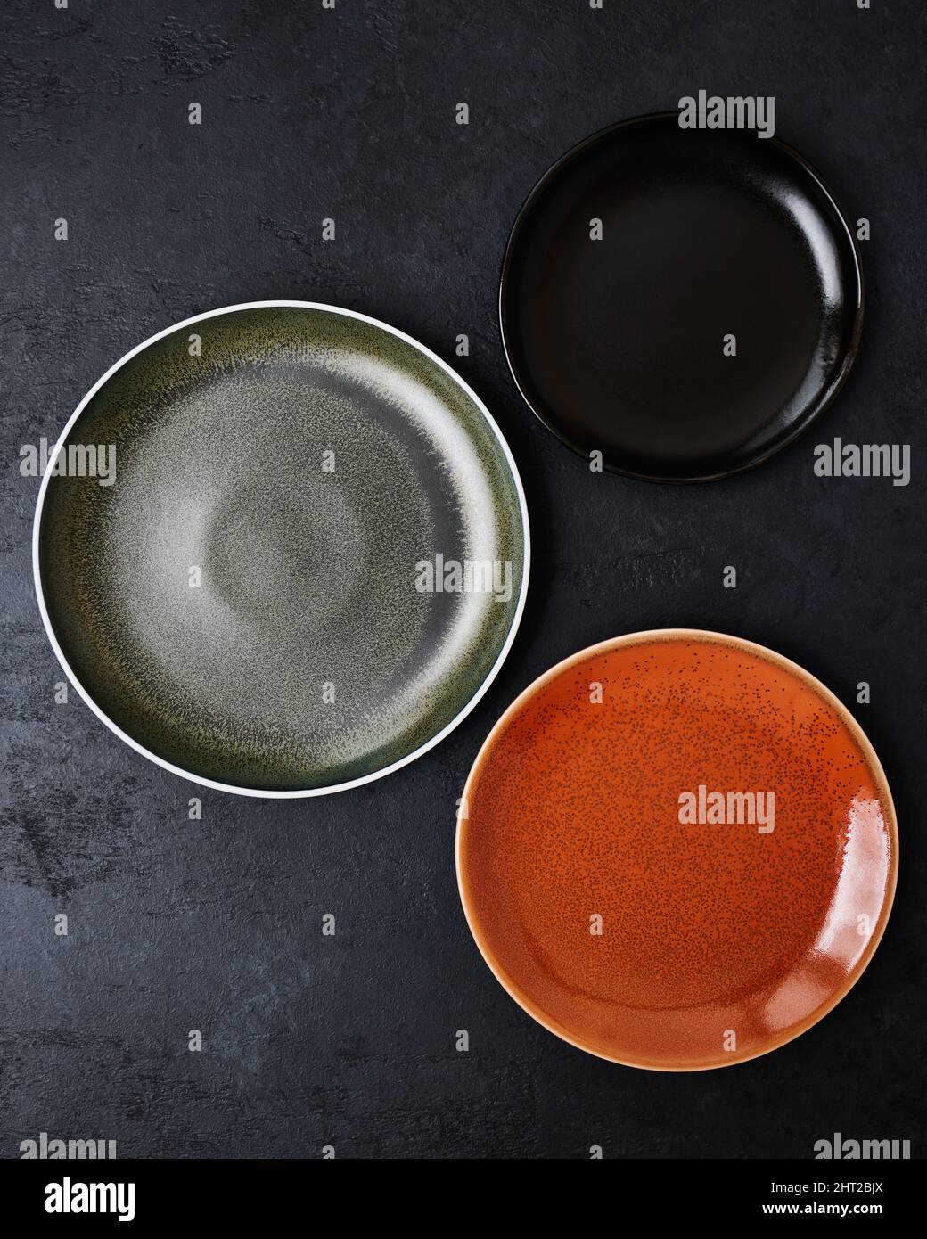 3 Empty round plates on black stone background with copy space, top ...