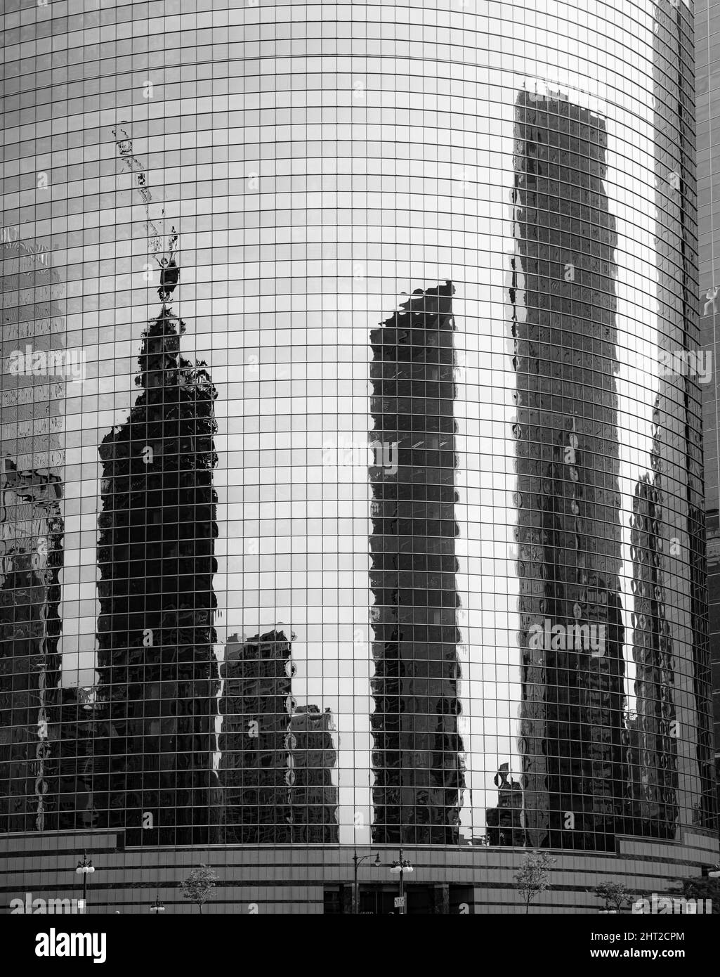 Grayscale vertical shot of a modern glass building reflecting other ...