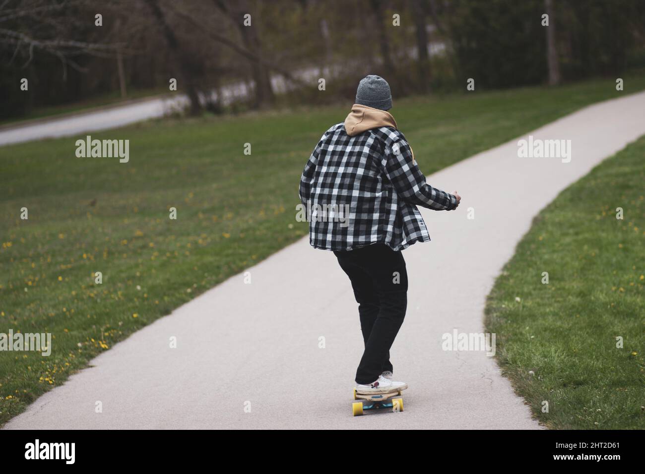 Back view of a young guy riding a skateboard in the park Stock Photo ...