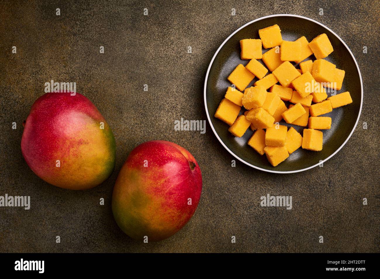 Mango is a tropical fruit. Two whole ripe mangoes and mango cubes in ...